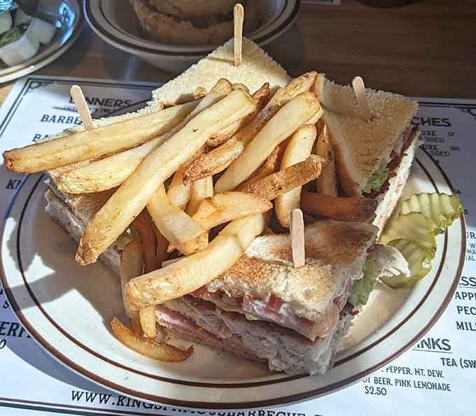 The King's Club sandwich arrives stacked high with fries piled on top, looking like it has absolutely nothing to prove.