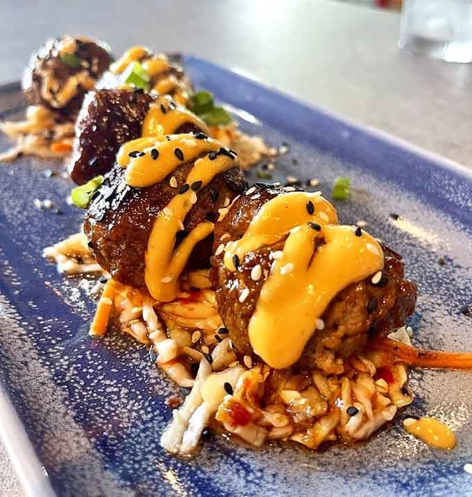 Korean BBQ meatballs lined up on a blue plate, bold, saucy, and completely impossible to share gracefully.