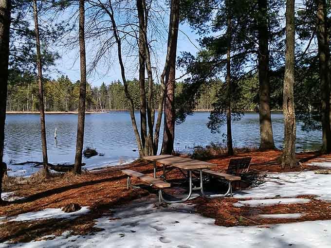 A snow-dusted picnic table beside a calm winter lake proves this enchanting park saves some of its best looks for the cold.