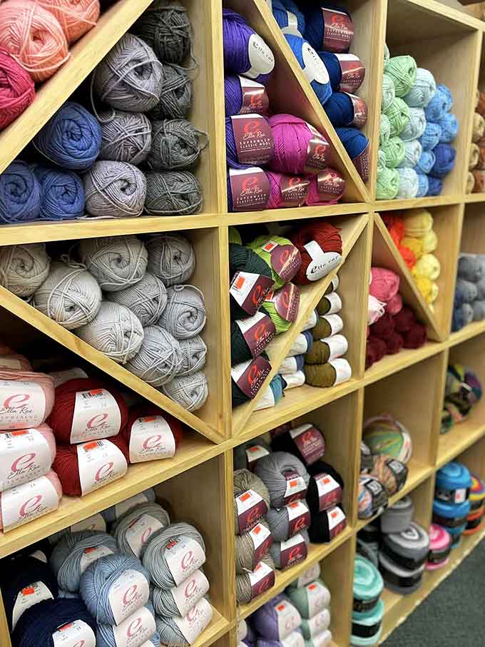 Ella Rae yarn in every color imaginable, neatly tucked into wooden cubbies like a rainbow decided to get organized.