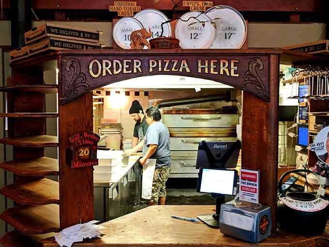 A hand-carved wooden arch that says "Order Pizza Here" like it means business. This counter has fed a lot of happy people.