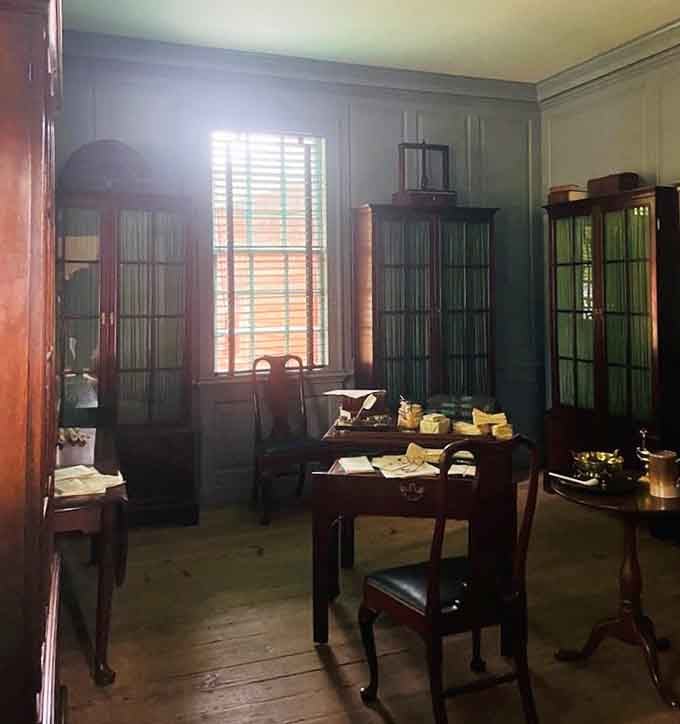 Sunlight pouring through the shutters onto a desk covered in papers, exactly how you'd imagine a founding father's workspace looking.