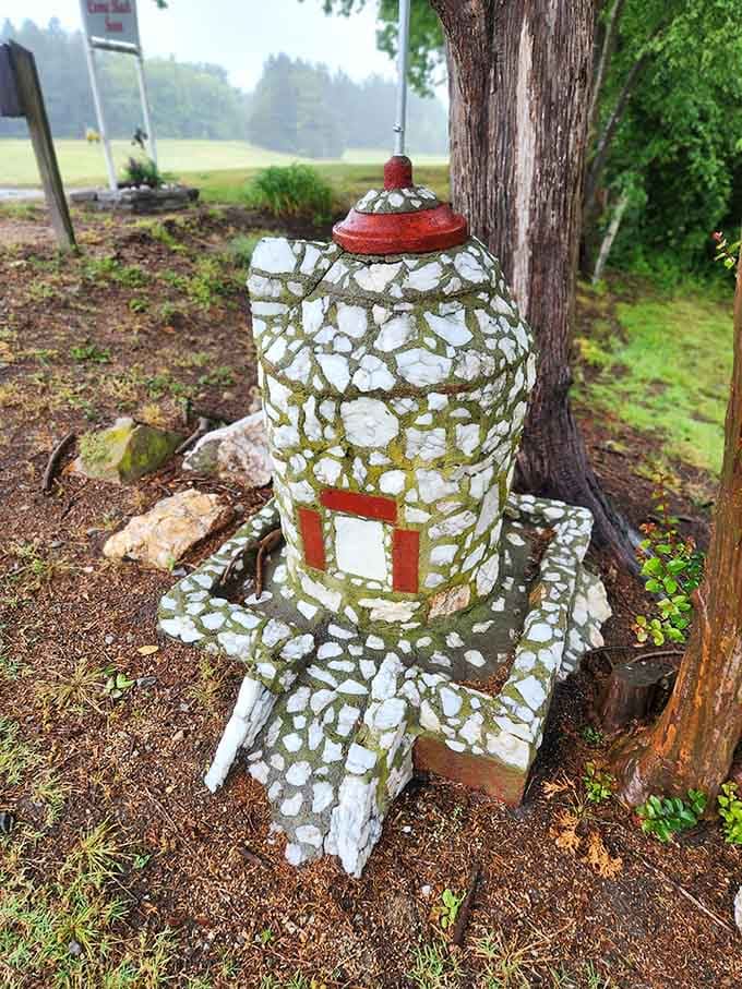 A small stone tower tucked beside a tree, quietly doing its job as the village's most charming landmark.