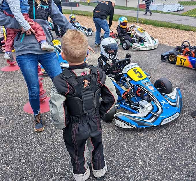 This tiny racer in full gear is already studying the competition with a seriousness that most adults reserve for tax season.