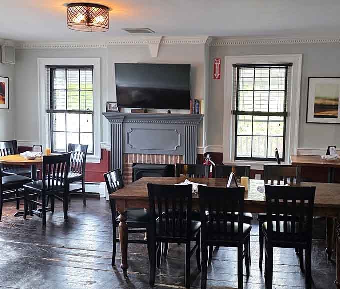 Tall windows, a classic fireplace mantel, and sunlight spilling across wooden tables, this dining room feels like a proper New England Sunday.