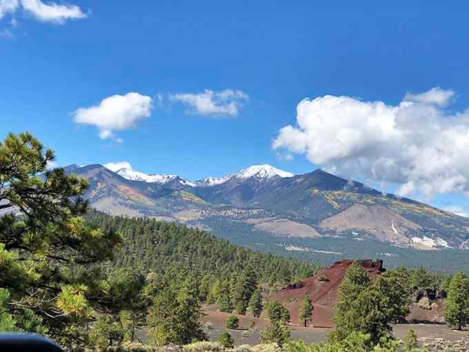 Snow-dusted San Francisco Peaks towering over red cinder formations and dark lava fields. Arizona's version of a masterpiece painting.