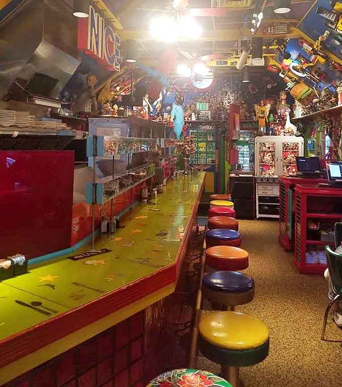 Mismatched bar stools, a bright yellow counter, and collectibles stacked to the rafters. This is the most entertaining seat in the house.