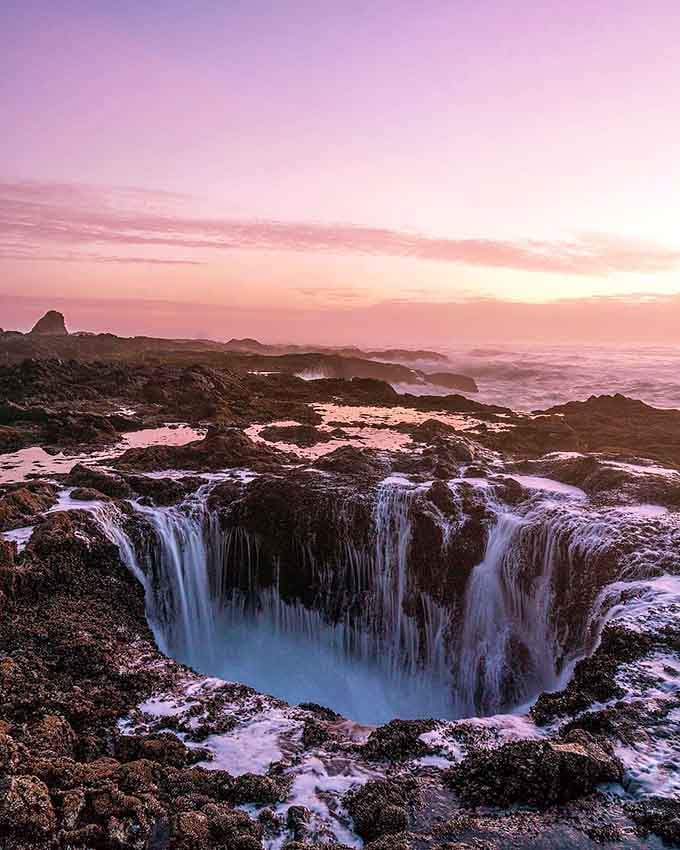 Pink skies and swirling water combine to create a scene that belongs on a fantasy novel cover.