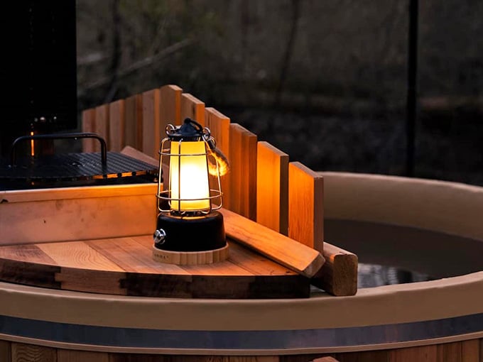 A small lantern glowing golden on the edge of a wooden soaking tub. Ambiance doesn't get more effortlessly perfect than this.
