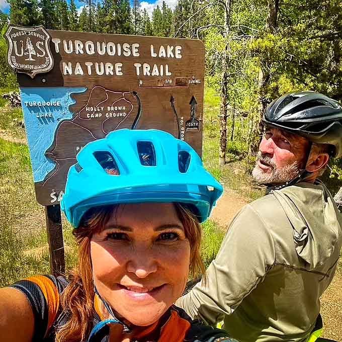 Helmets on, smiles ready, and the Turquoise Lake Nature Trail sign officially giving two cyclists permission to have fun.