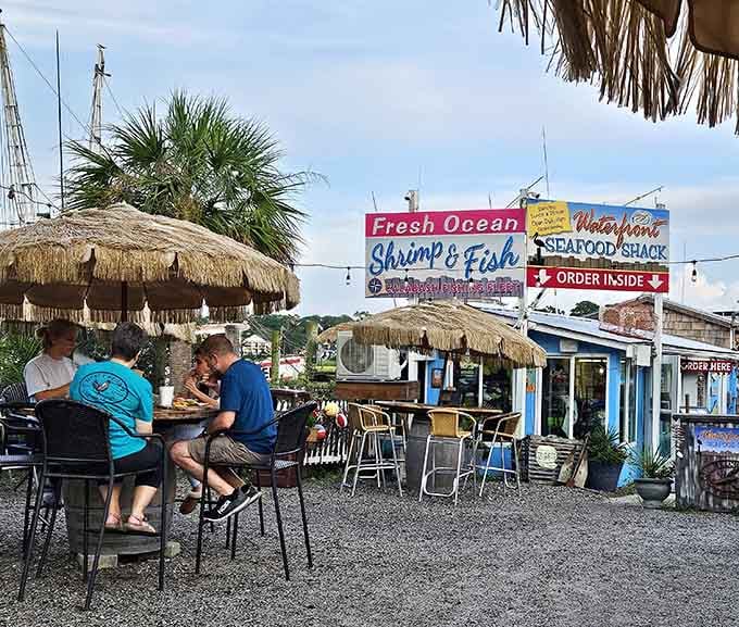 Tiki umbrellas, gravel underfoot, and fresh seafood on the table. This outdoor setup is casual coastal dining done right.
