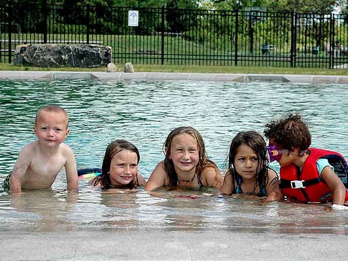 Five kids lined up at the shallow edge, grinning like they just discovered the greatest secret in Minneapolis.