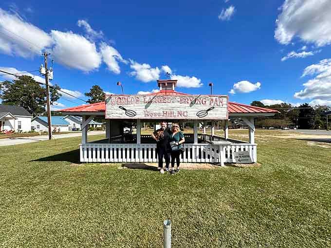 Smiling visitors in front of the bold red-lettered sign, proof that some road trips are absolutely worth it.