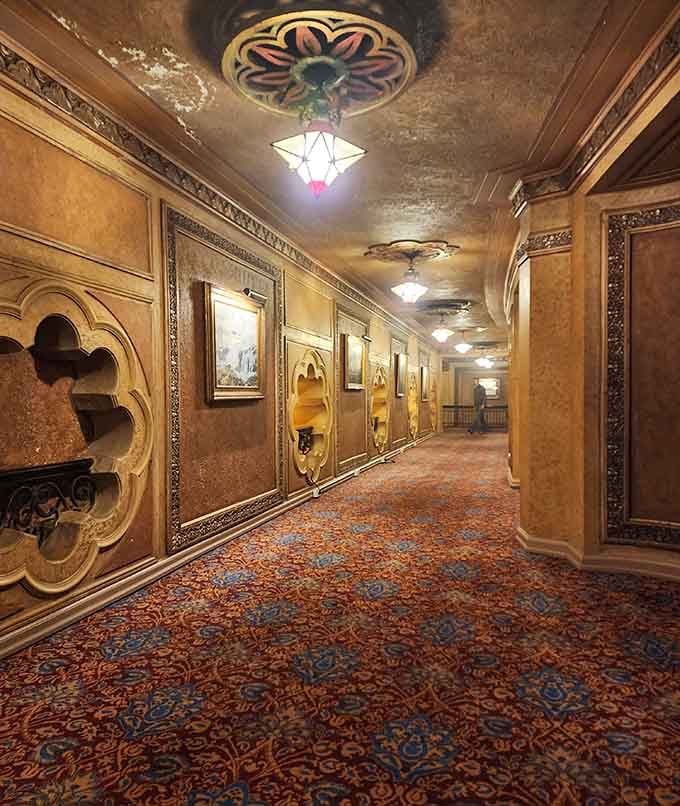 A corridor lined with framed artwork and ornate ceiling fixtures, proving that even the hallways here refused to be ordinary.