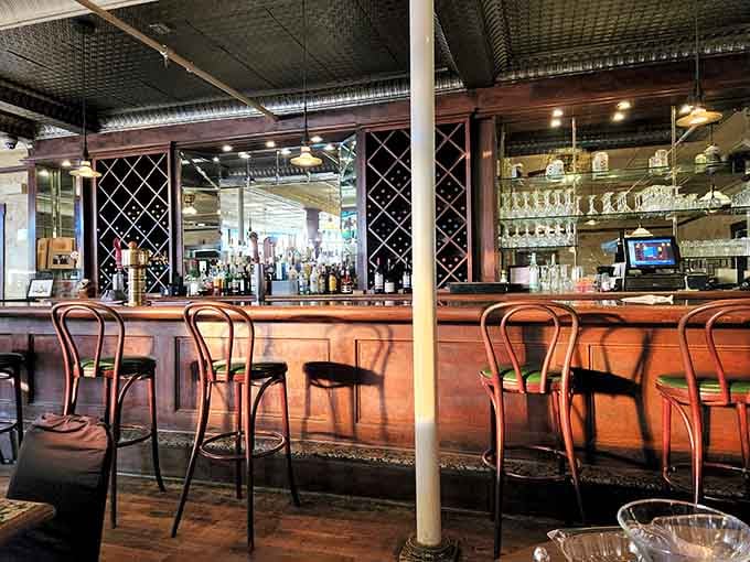 A proper wooden bar with wine racks, mirrored shelves, and pressed tin overhead. This is where good evenings begin.