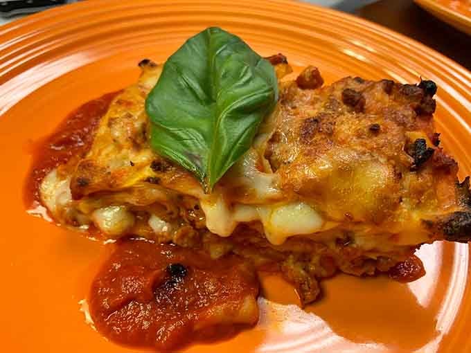 Bubbling baked meat lasagna layered with melted cheese and tomato sauce, topped with basil like a crown it earned.