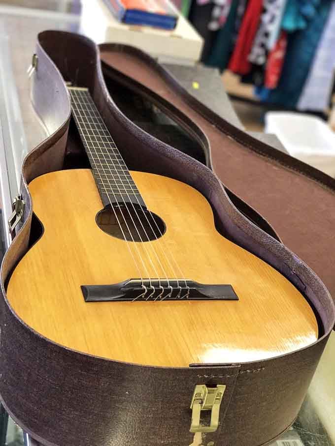 An acoustic guitar resting in its case, waiting patiently for someone to give it a second musical life.