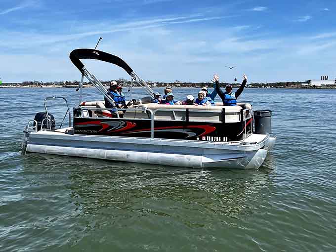 Out on the Chesapeake Bay, hands raised and life jackets on, this crew has clearly figured out what a perfect afternoon actually looks like.