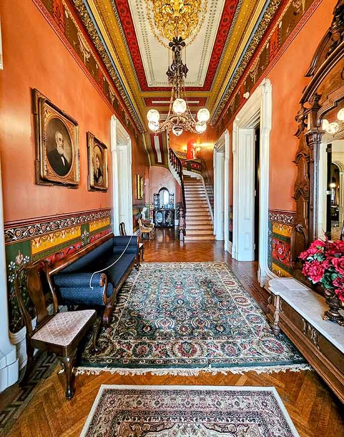 The foyer sets the tone immediately, rich colors, parquet floors, and a staircase that means serious business.