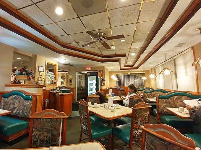 Tufted green booths and ornate chairs under a ceiling fan, a dining room that time treated kindly.