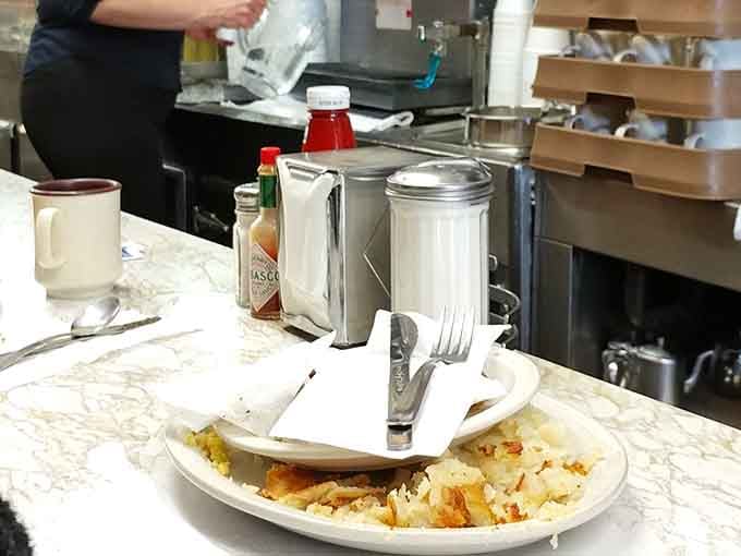 Salt, pepper, Tabasco, and a fork waiting patiently, the simple table setup of a place that lets the food do the talking.