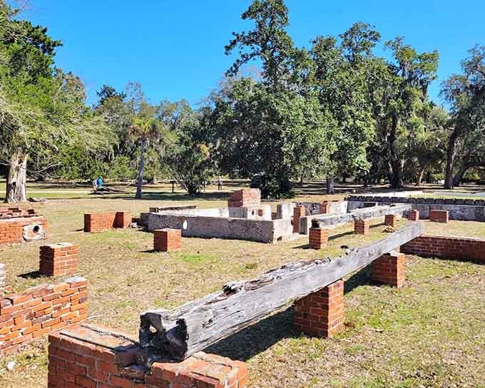 Low brick foundation walls stretch across the sunny lawn like a floor plan drawn by history itself.