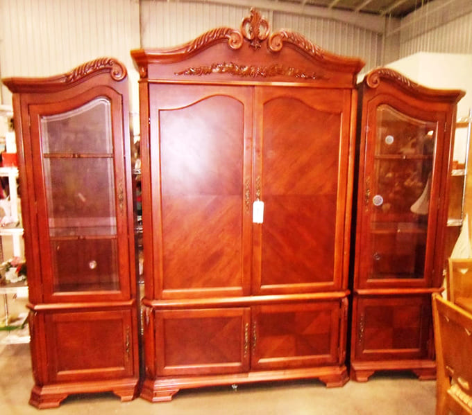 An ornate mahogany entertainment center with carved details and glass doors, the kind of piece that makes you stop and say wow.