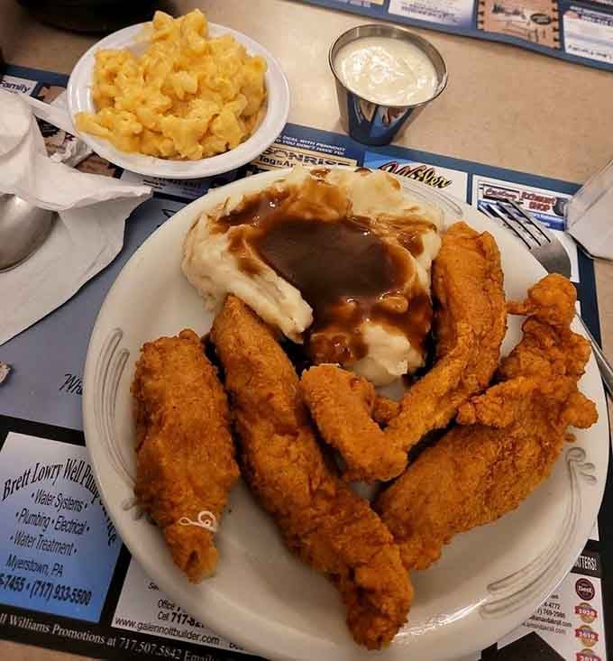 Crispy chicken fingers over a cloud of mashed potatoes with gravy, plus mac and cheese on the side. Comfort food at its finest.
