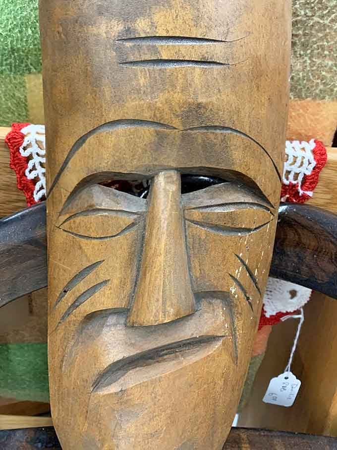 A hand-carved wooden mask stares back at you with the quiet confidence of someone who has seen everything.