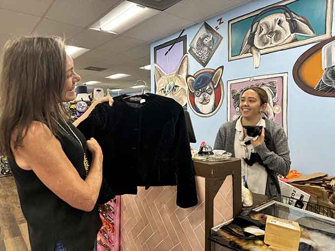 Smiles at the checkout counter, a kitten in hand, and painted animal portraits watching over everything warmly.