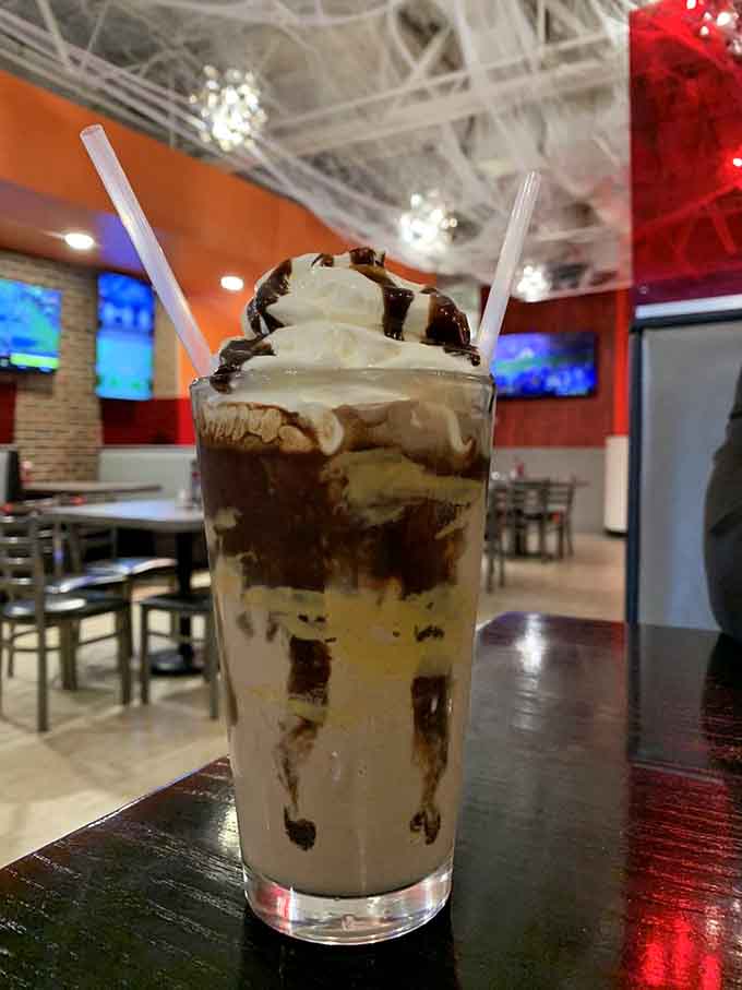 Two straws, whipped cream, chocolate drizzle, and the entire Flamme Burger dining room reflected behind it like a dessert hall of fame.