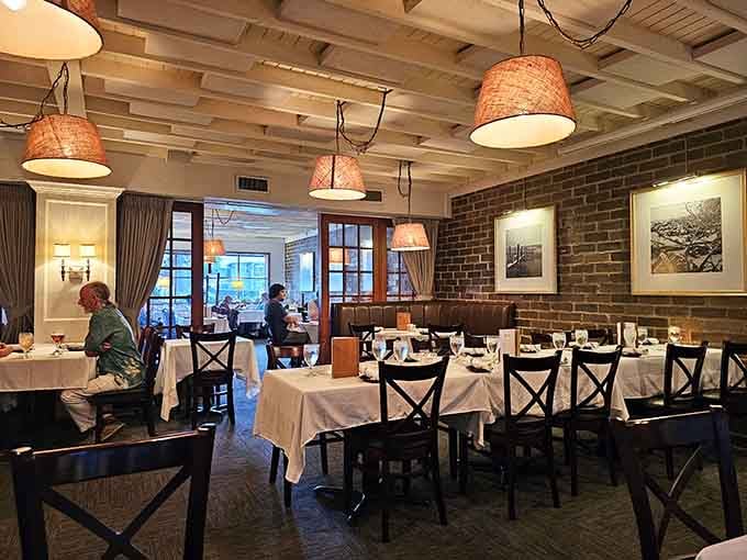 White tablecloths, warm pendant lights, exposed brick, and framed coastal photography. The dining room earns every compliment it gets.
