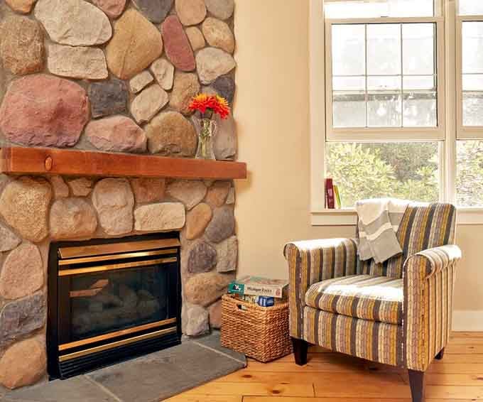 A river rock fireplace and a striped armchair. This corner was made for doing absolutely nothing.