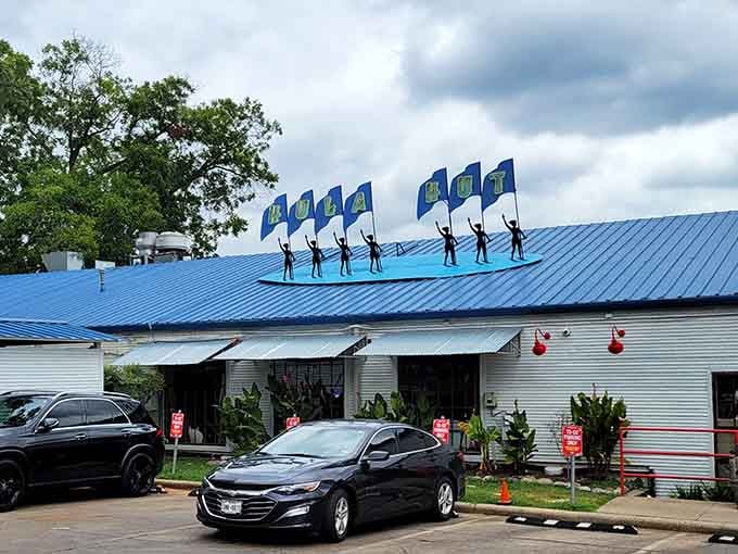 Silhouette dancers waving flags on a blue rooftop, the Hula Hut announces itself before you even find parking.
