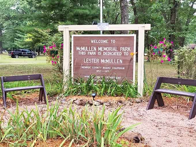 The welcome sign for McMullen Memorial Park, dedicated to Lester McMullen, stands proudly flanked by cheerful flowers and sturdy benches.