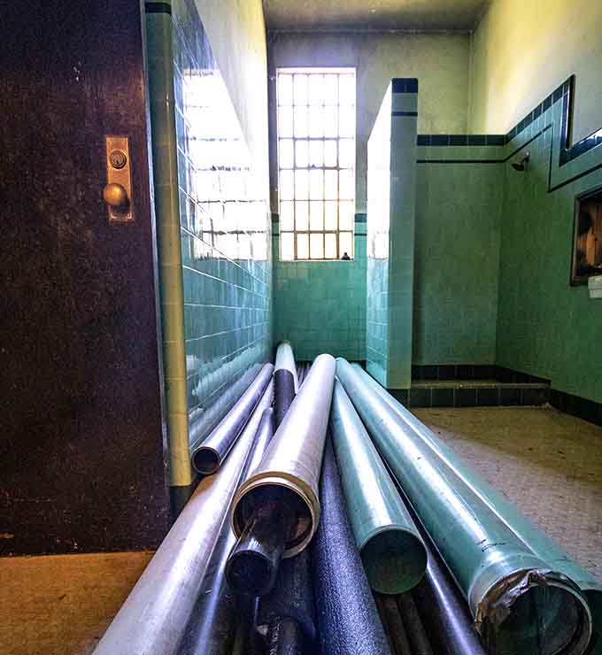 Teal tiles and bundled pipes fill a bathroom that clearly hasn't hosted a renovation committee meeting in quite some time.
