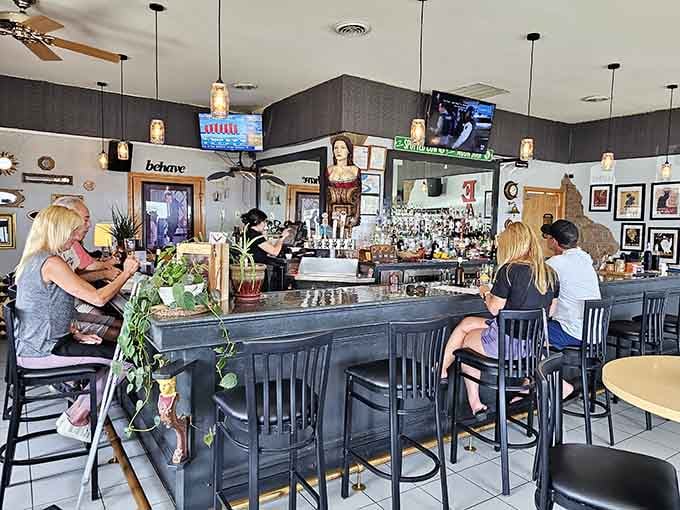 A lively bar scene with pendant lights, a well-stocked back bar, and a "behave" sign that suggests the fun here is entirely real.
