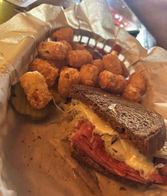 A Reuben sandwich on dark rye with tater tots, the kind of combination that deserves its own standing ovation.