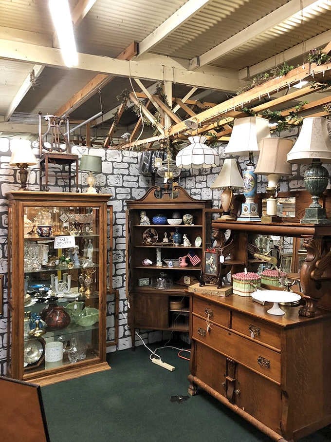 Oak furniture, stained glass lamp shades, and glassware crowded together against a painted brick wall, each piece telling its own quiet story.