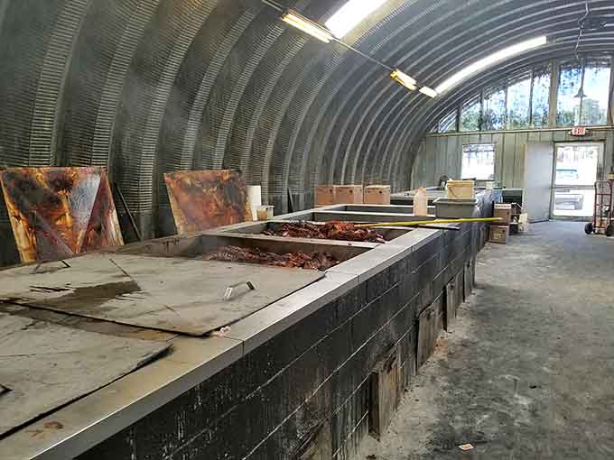 Inside that curved metal smokehouse, whole hogs cook over real wood in long, blackened pits built for serious business.