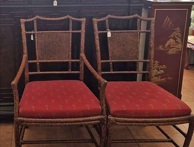 A pair of handsome rattan chairs with rich red cushions, ready to anchor a reading nook or a very stylish porch.