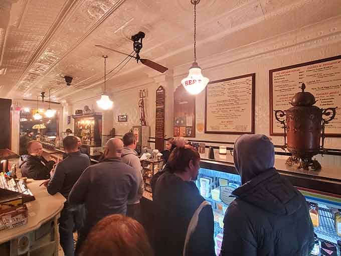 A full house gathered around the counter, warm light overhead, everyone leaning in slightly, united by the universal language of ice cream.