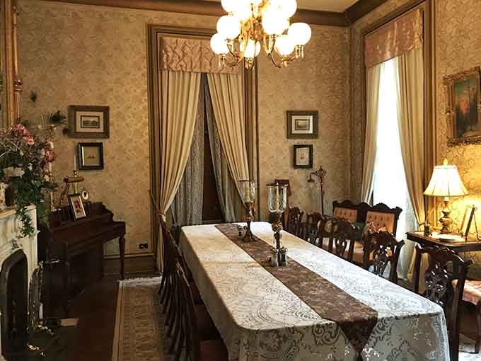 A formal dining table set with lace linens and candlesticks, surrounded by gold damask walls. This room takes dinner seriously, and honestly, so should you.