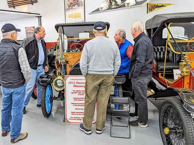 Visitors huddle around a brass-era beauty, captivated by craftsmanship from a bygone era of motoring.