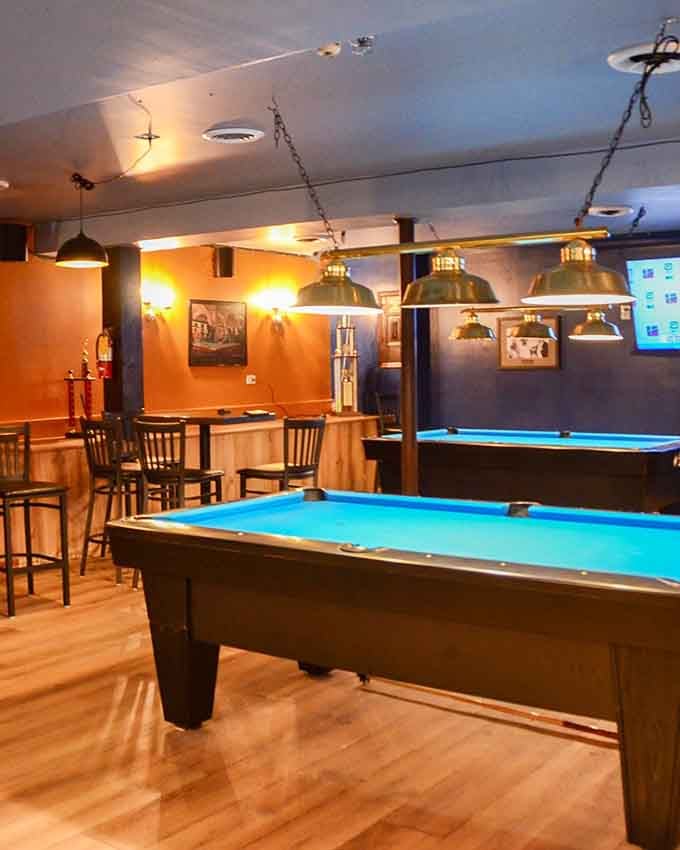 Pool tables in warm lighting create the perfect spot for friendly competition and trash talk between bites of your favorite meal.