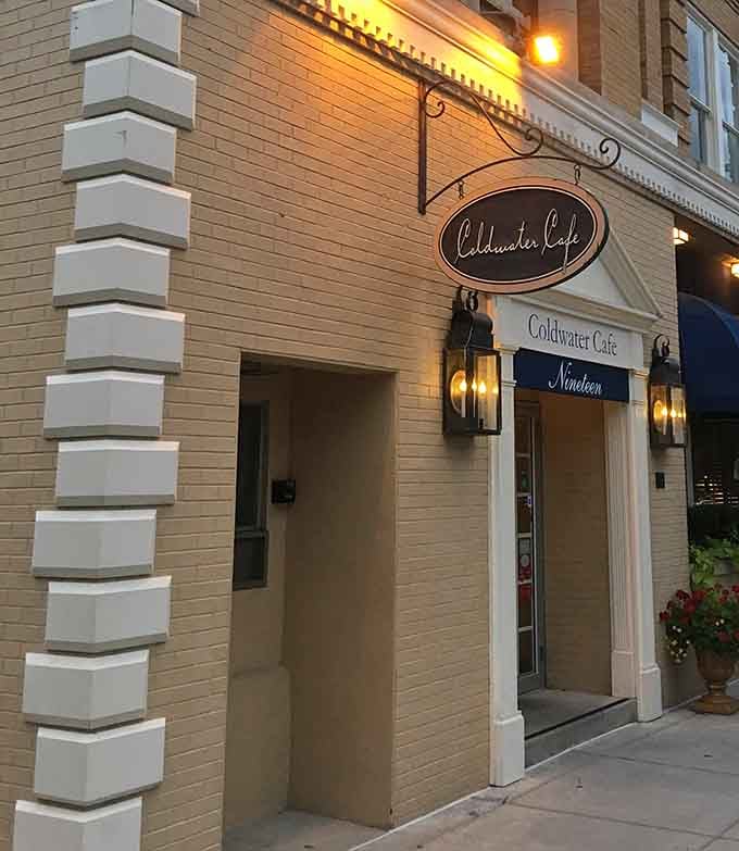Coldwater Cafe glowing warmly at dusk, lantern light spilling onto the brick sidewalk, whispering that dinner here is going to be just right.