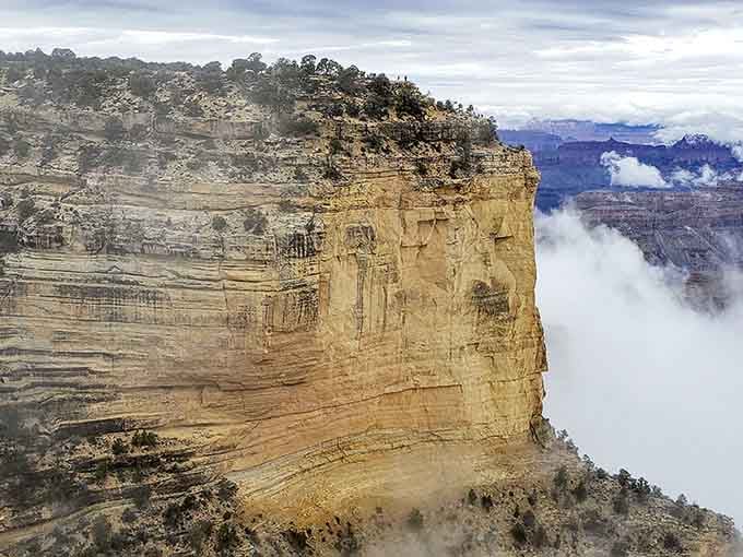 Clouds hugging a towering sandstone cliff face, as if even the weather can't resist getting close to something this magnificent.