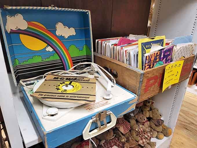 A rainbow-lidded portable record player sitting next to a crate of 45s. Happiness, apparently, fits in a suitcase.