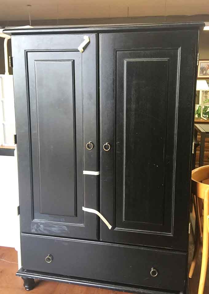 A striking black armoire with brass ring pulls standing tall, the kind of statement piece that anchors an entire room effortlessly.