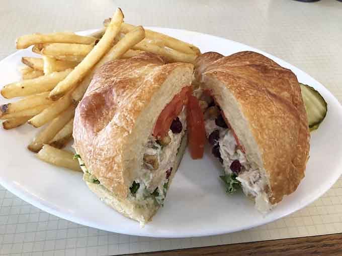 A chicken salad croissant that looks like it was assembled with genuine care and a side of perfectly golden fries.